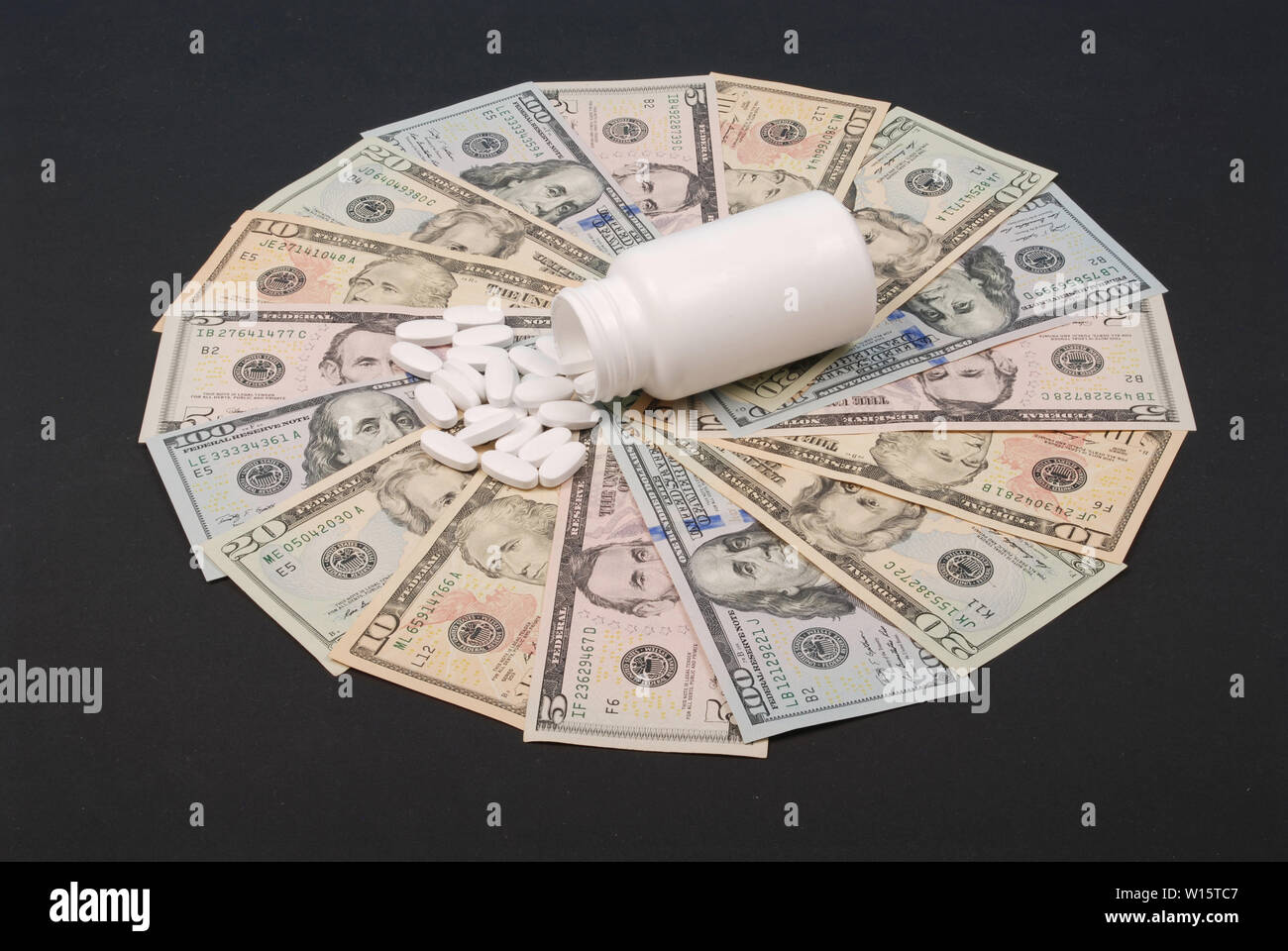 Pills spilling out of pill bottle on money, in the shape of a circle ...
