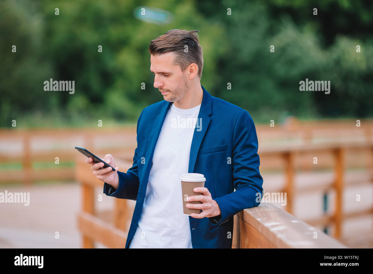 Happy young urban man working and drinking coffee in european city ...