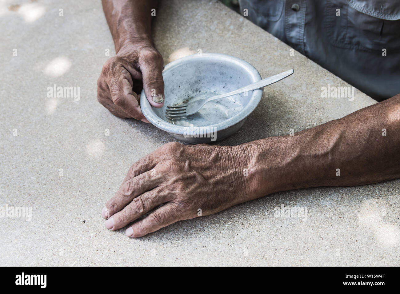 Hungry. Poor old man's hands an empty bowl. Selective focus. Poverty in ...