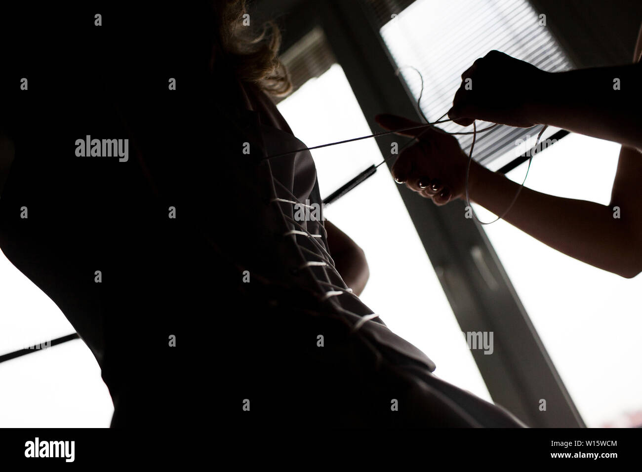 Bride from the back. Lacing the wedding dress Stock Photo - Alamy