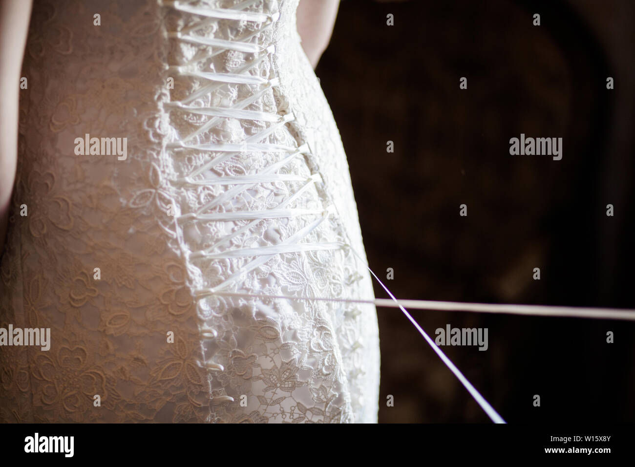 Bride from the back. Lacing the wedding dress Stock Photo - Alamy