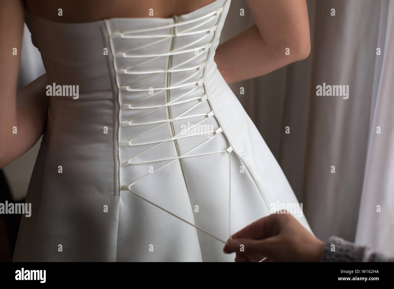 Bride from the back. Lacing the wedding dress Stock Photo - Alamy