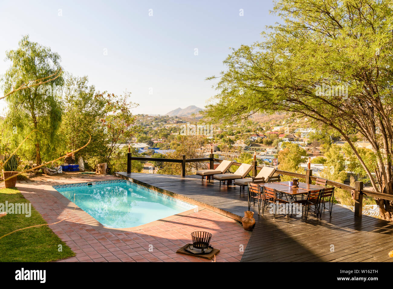 Swimming pool and sunloungers on a patio overlooking Windhoek, Namibia ...