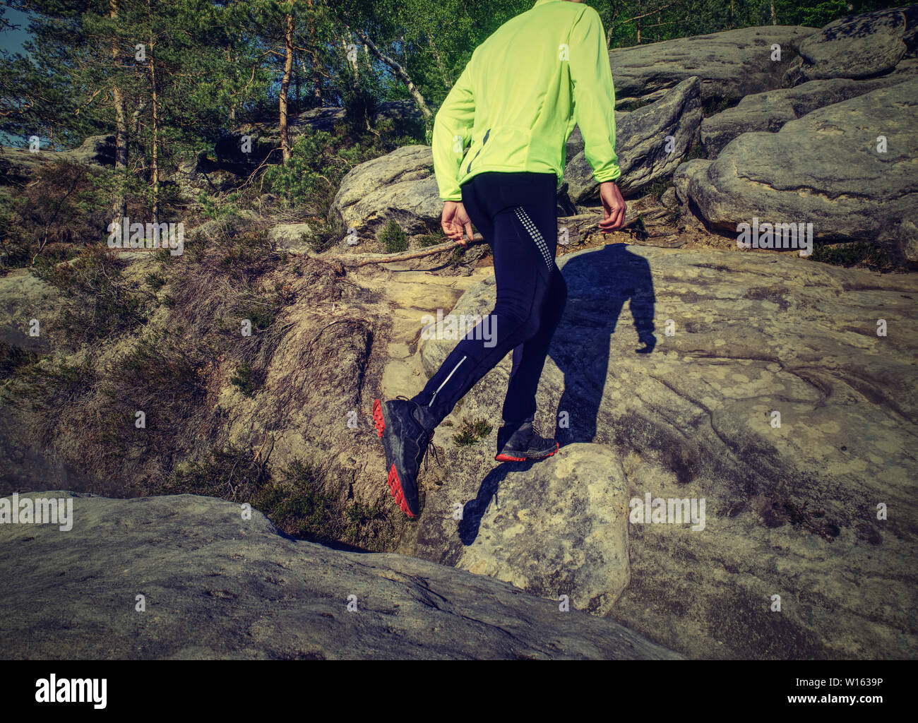 Fitness man trail runner running to rocky mountain top on cracked rocky ...