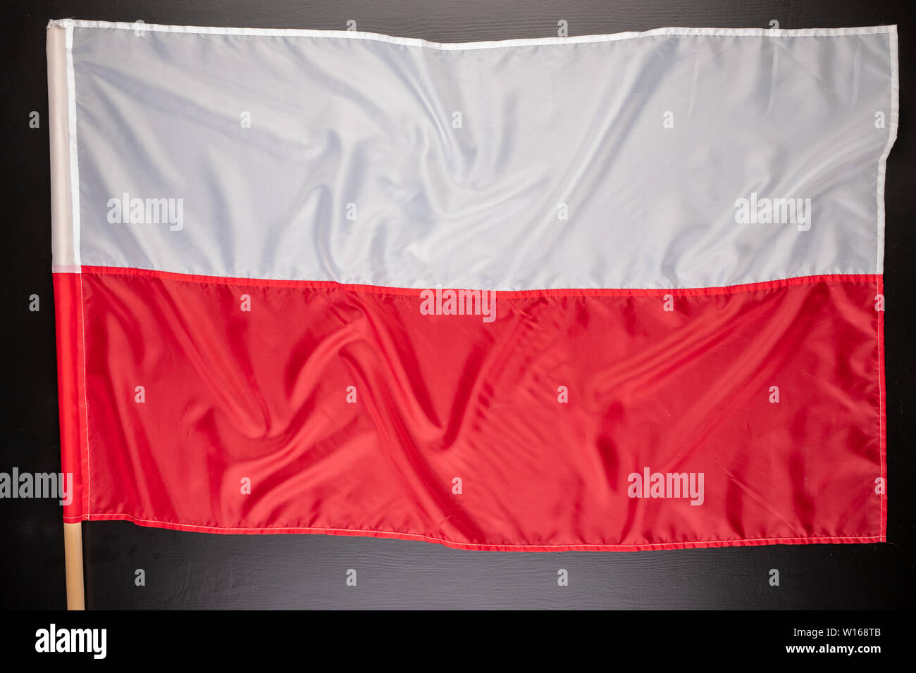 Polish flag on a dark table. A flag attached to a wooden spar. Dark ...