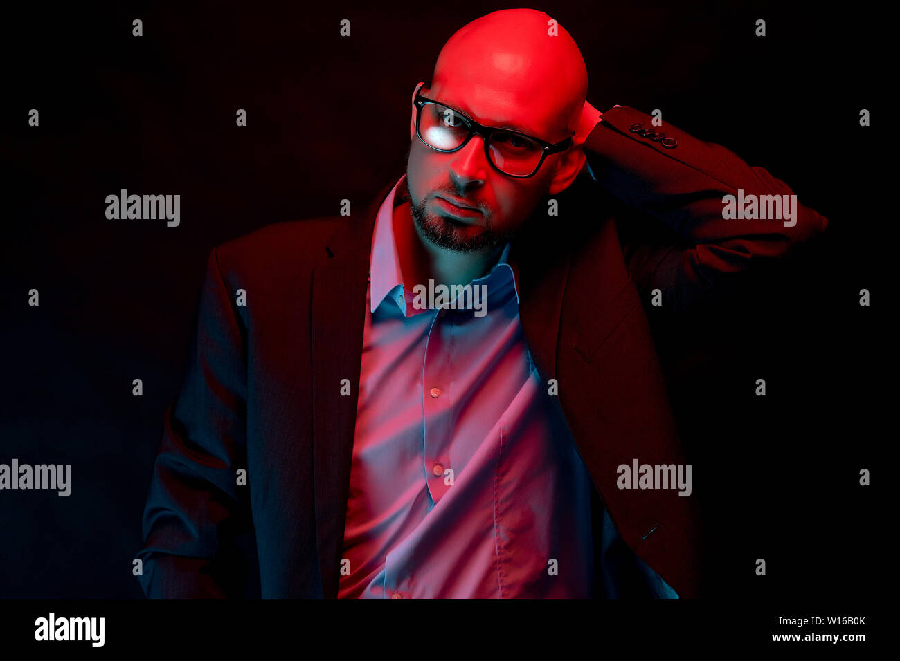 Attractive bald man with beard with glasses on neon light background ...