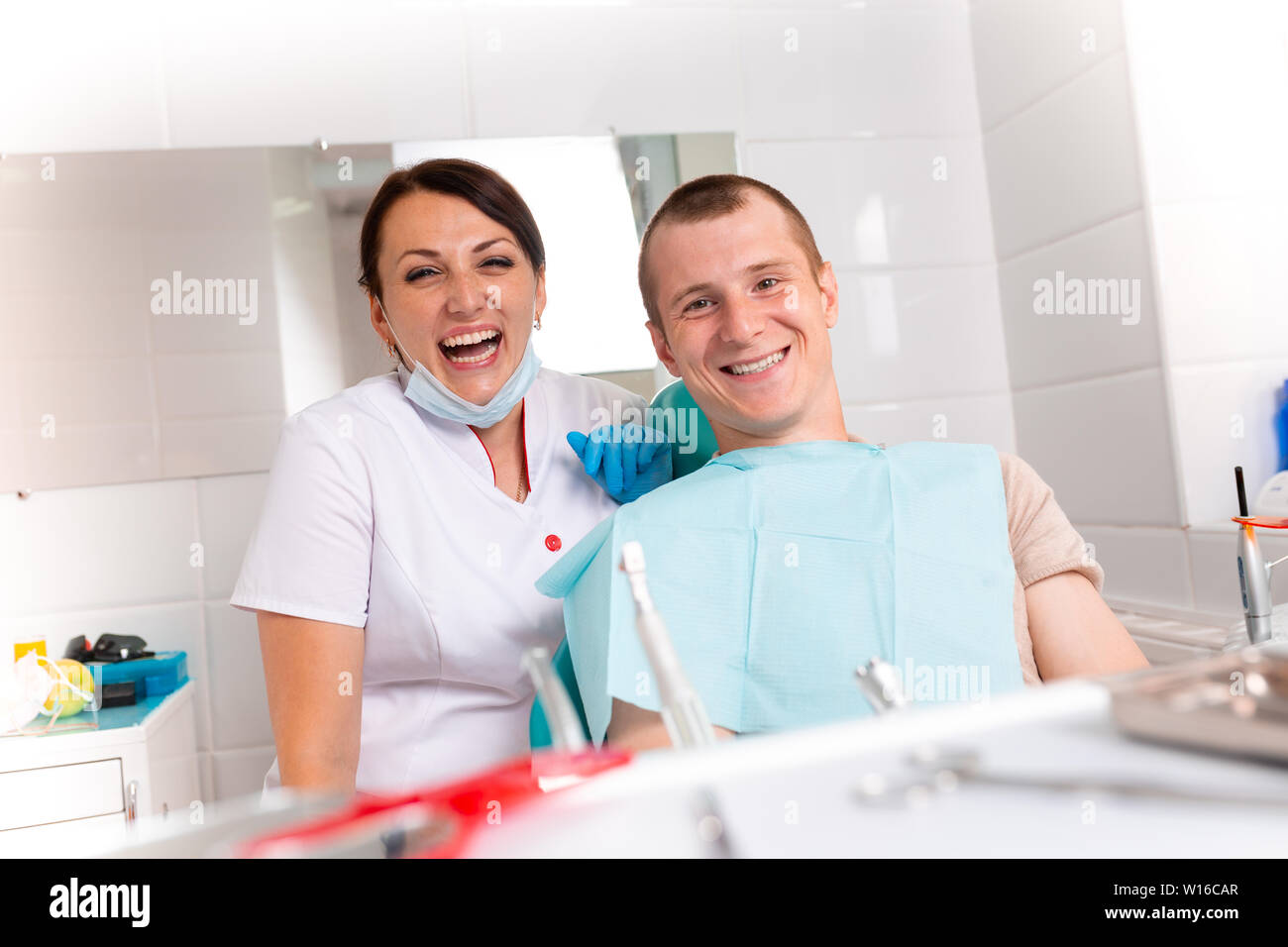 The dentist and her happy patient look at the camera and smile ...