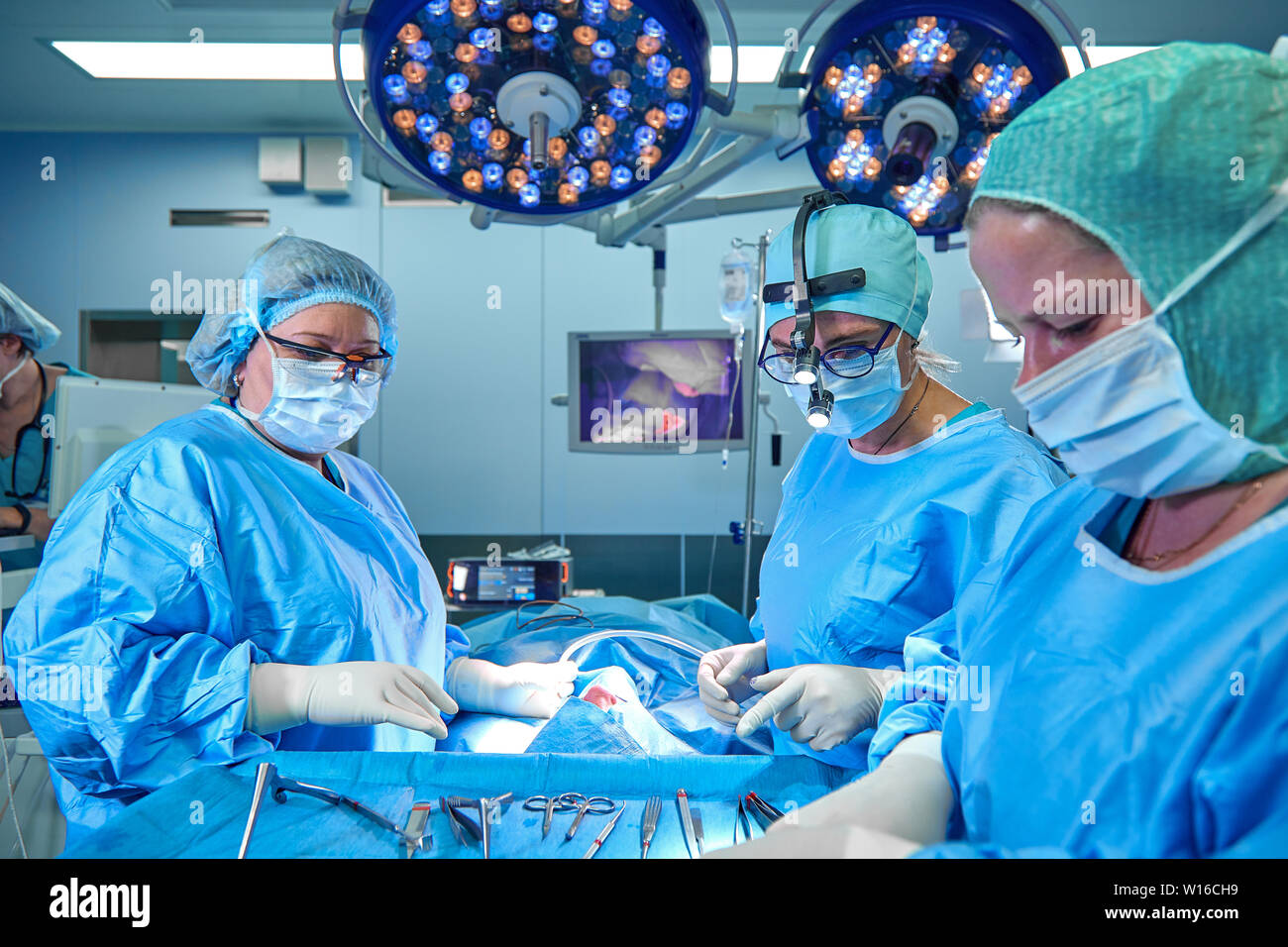 A surgeon's team in uniform performs an operation on a patient at a ...