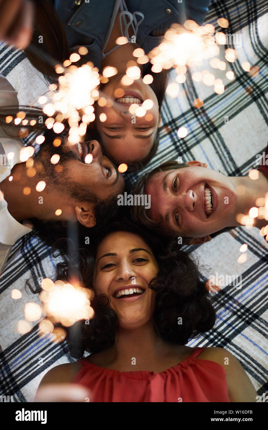 Low angle portrait of four young people holding sparkling lights ...