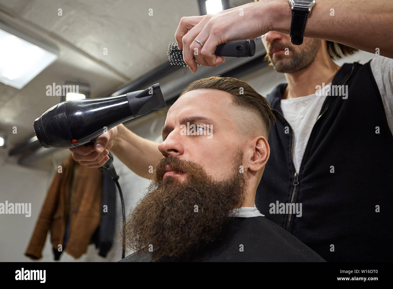 Brutal guy in modern Barber Shop. Hairdresser makes hairstyle a man ...