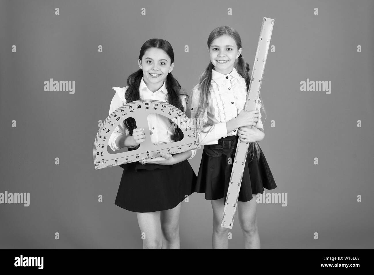 Having a private lesson. Cute schoolgirls holding protractor and ruler ...