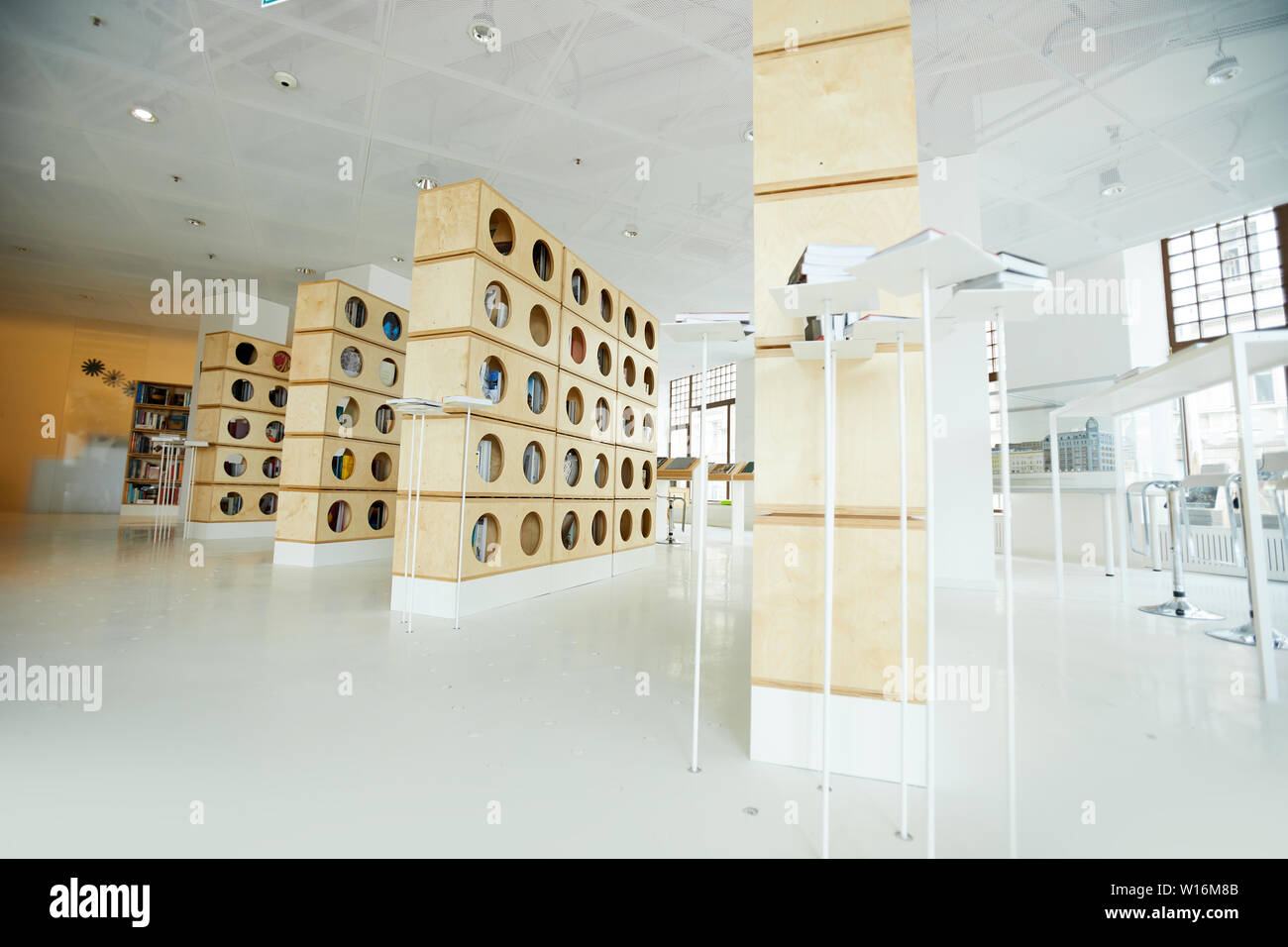 Modern interior of bookstore with wooden bookcases and high tables for ...