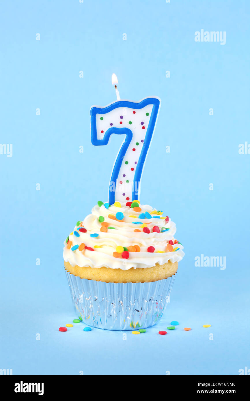 Iced birthday cupcake with with lit number 7 candle and sprinkles Stock ...