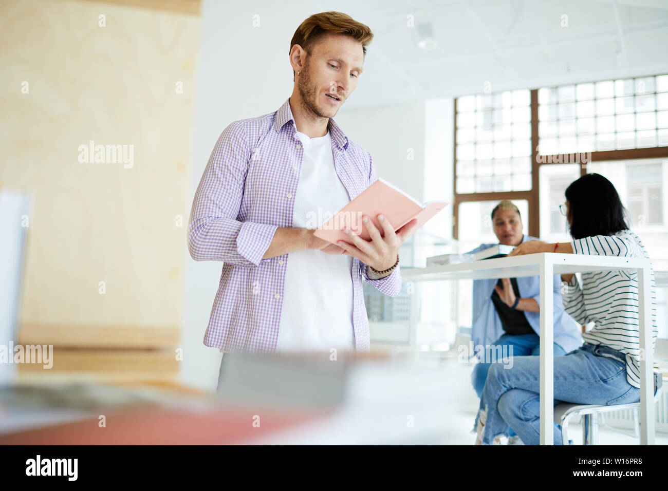 Concentrated curious young man with stubble standing in spacious ...