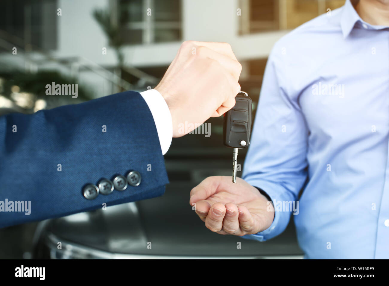 Salesman giving man a key from his new car Stock Photo - Alamy