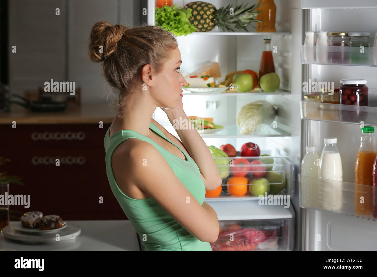 Beautiful young woman looking into fridge at night Stock Photo - Alamy
