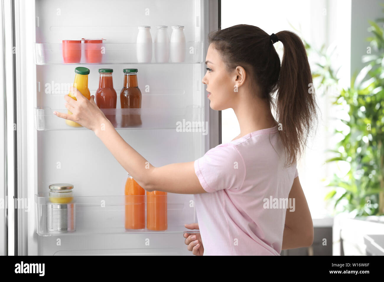 Woman taking food out of fridge at home Stock Photo - Alamy