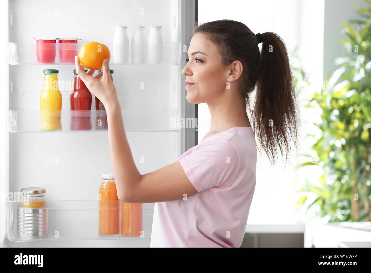 Woman taking food out of fridge at home Stock Photo - Alamy