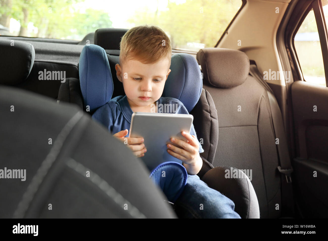 Little boy with tablet computer buckled in car seat Stock Photo - Alamy