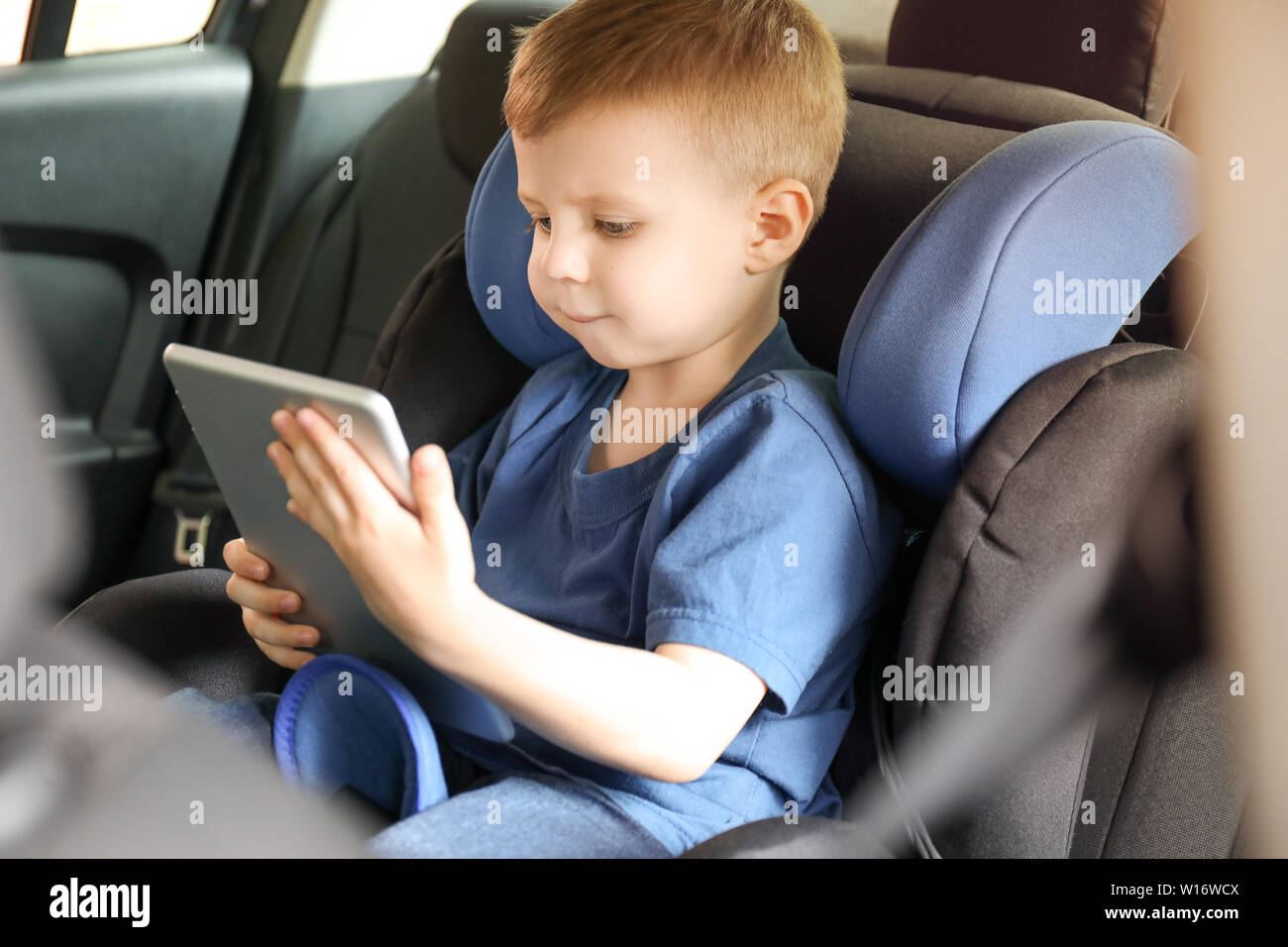 Little boy with tablet computer buckled in car seat Stock Photo - Alamy