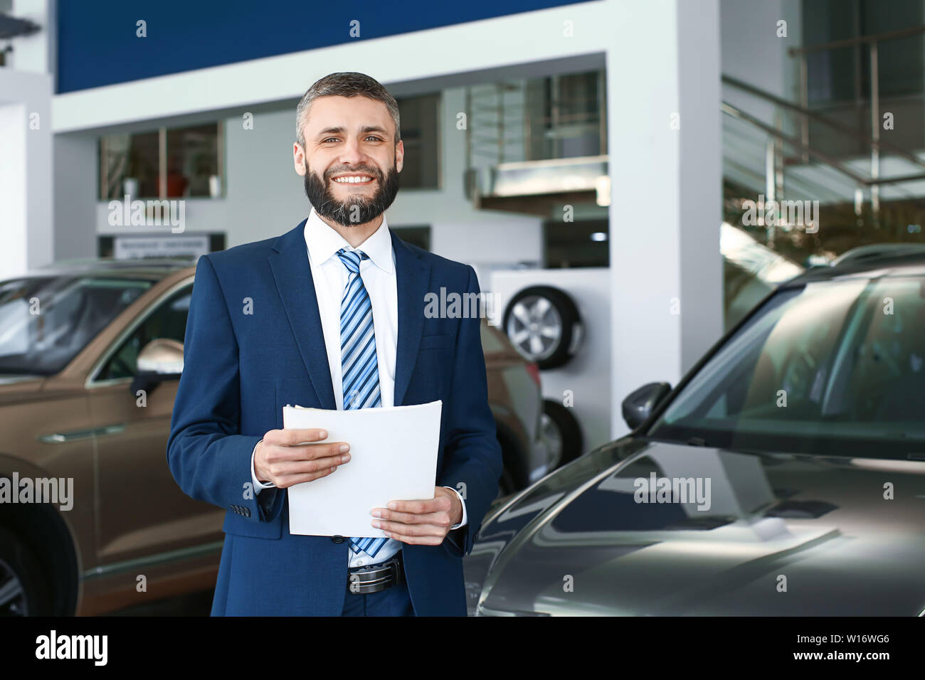 Salesman in modern car showroom Stock Photo - Alamy