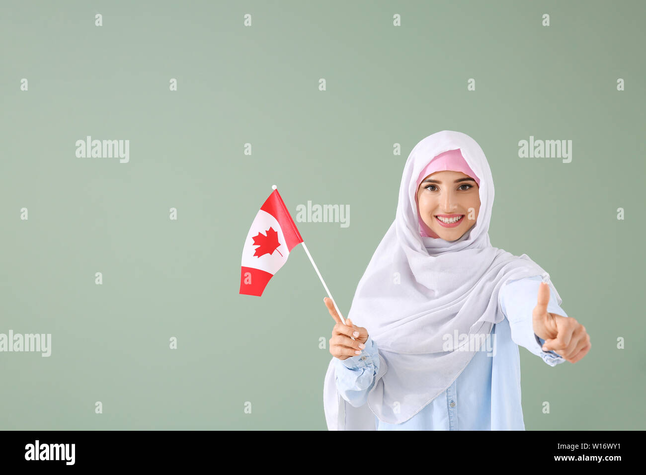 Young Muslim woman with Canadian flag on color background Stock Photo ...