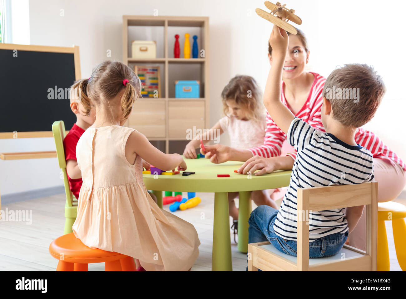 Nursery teacher with cute little children in kindergarten Stock Photo ...