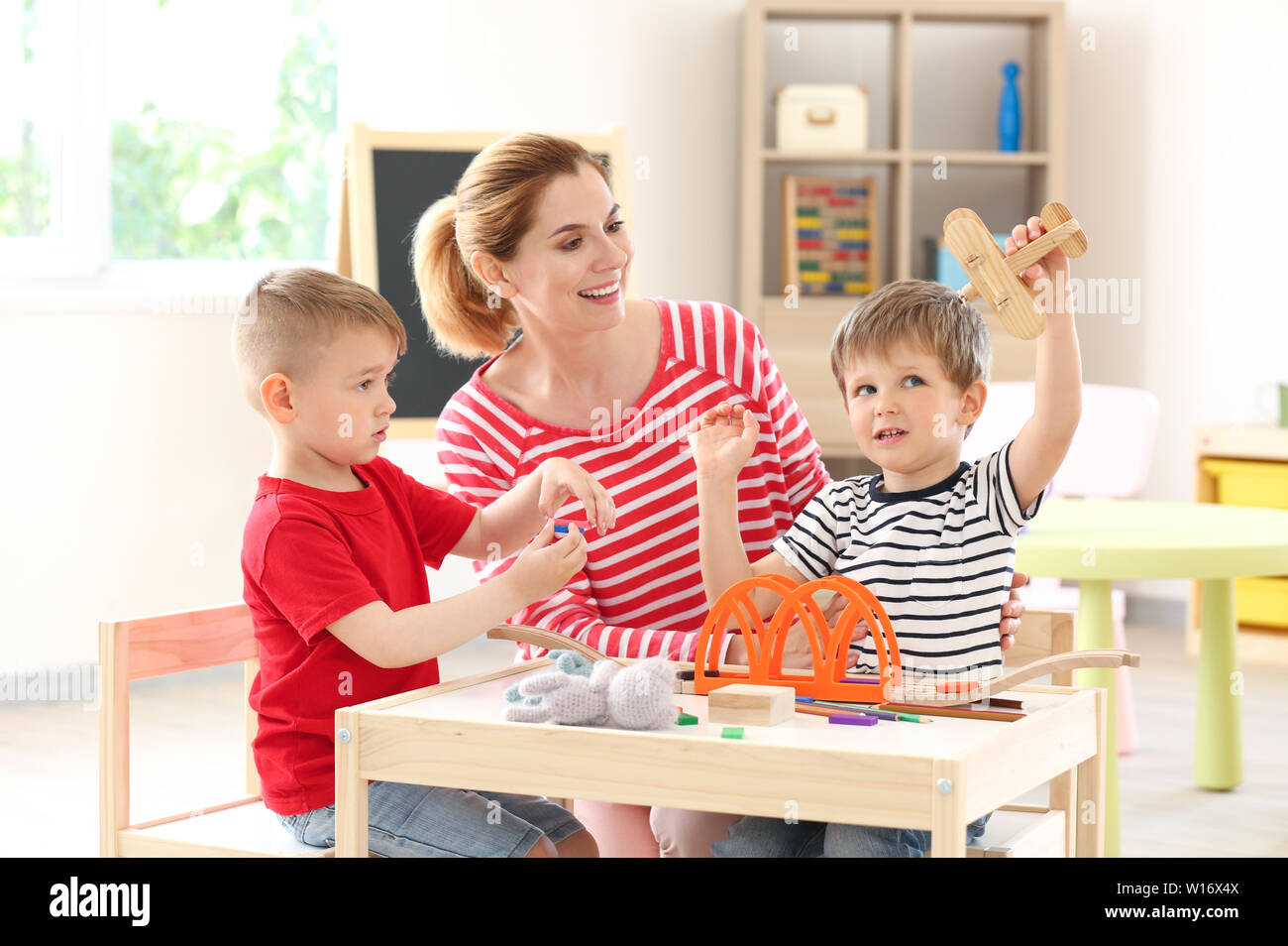 Nursery teacher with cute little children in kindergarten Stock Photo ...