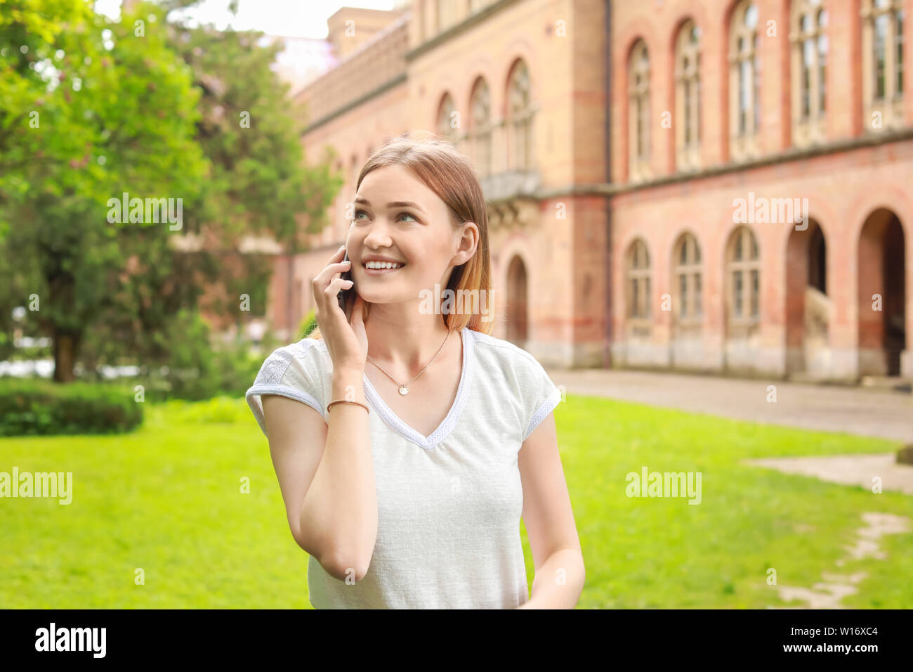 Female tourist talking by mobile phone near beautiful old building ...