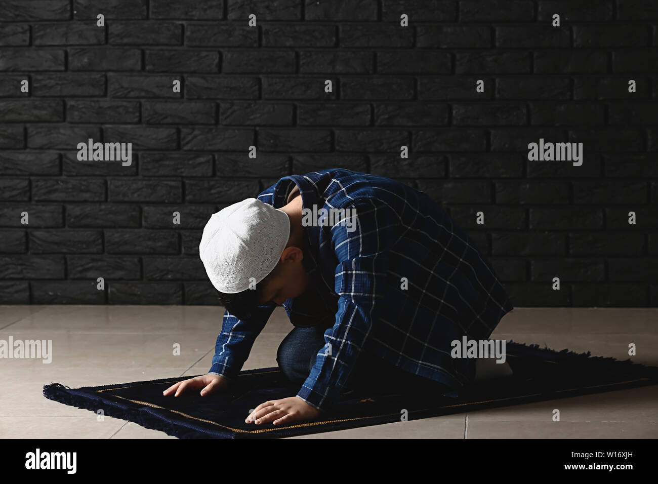 Little Muslim boy praying against dark wall Stock Photo - Alamy