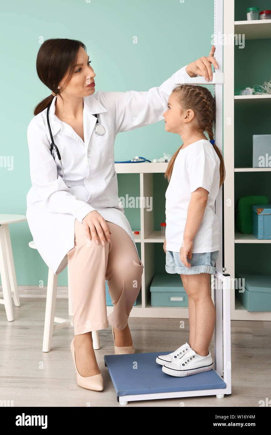 Female doctor measuring height of little girl in hospital Stock Photo ...