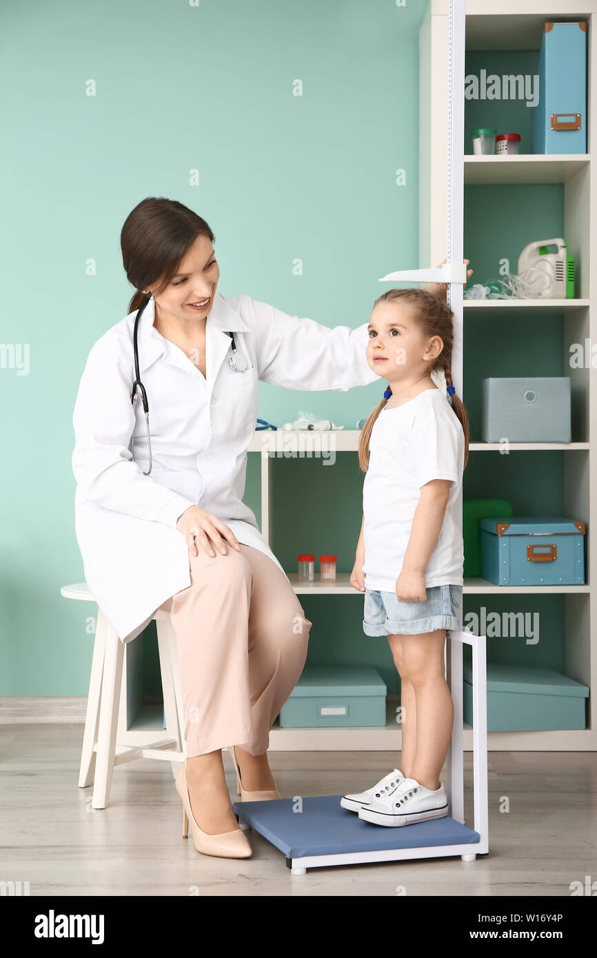 Female doctor measuring height of little girl in hospital Stock Photo ...