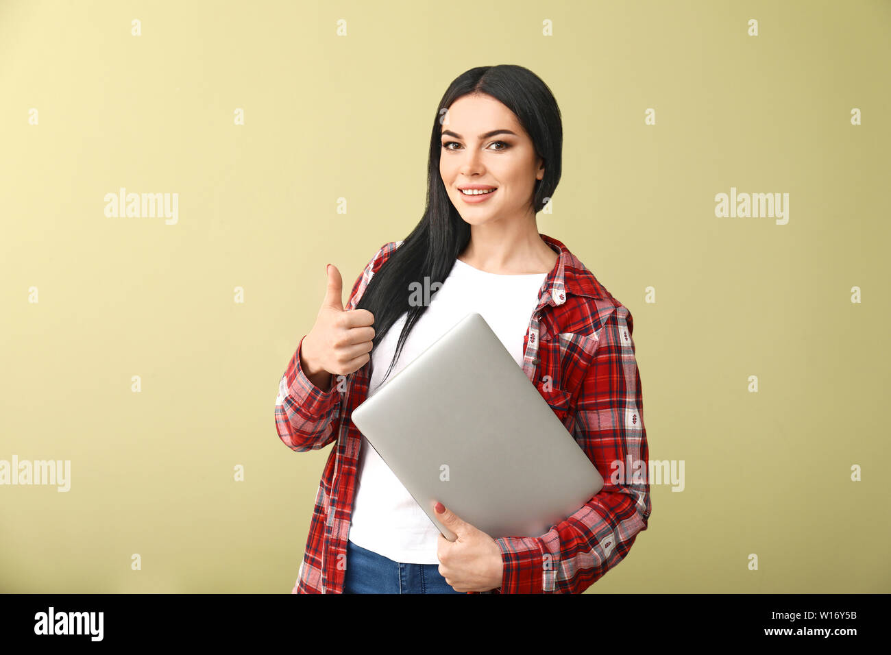Female programmer with laptop showing thumb-up gesture on color ...