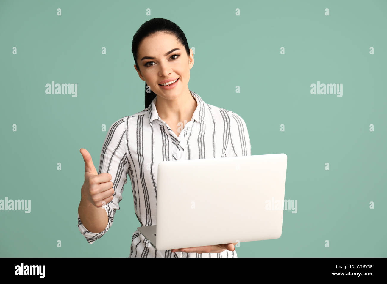 Female programmer with laptop showing thumb-up gesture on color ...