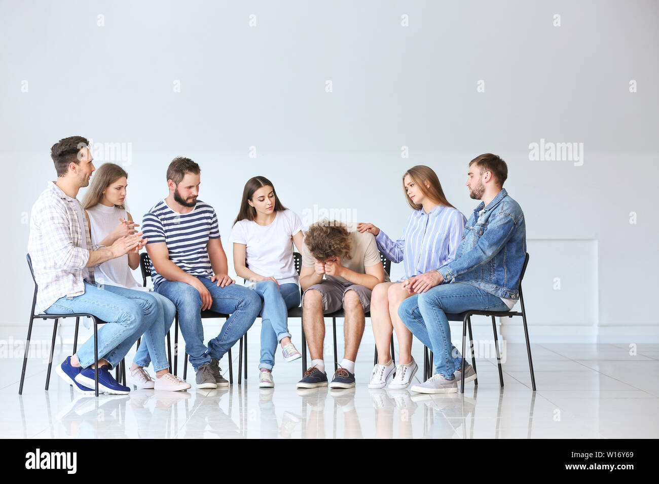 Young people calming man at group therapy session Stock Photo - Alamy