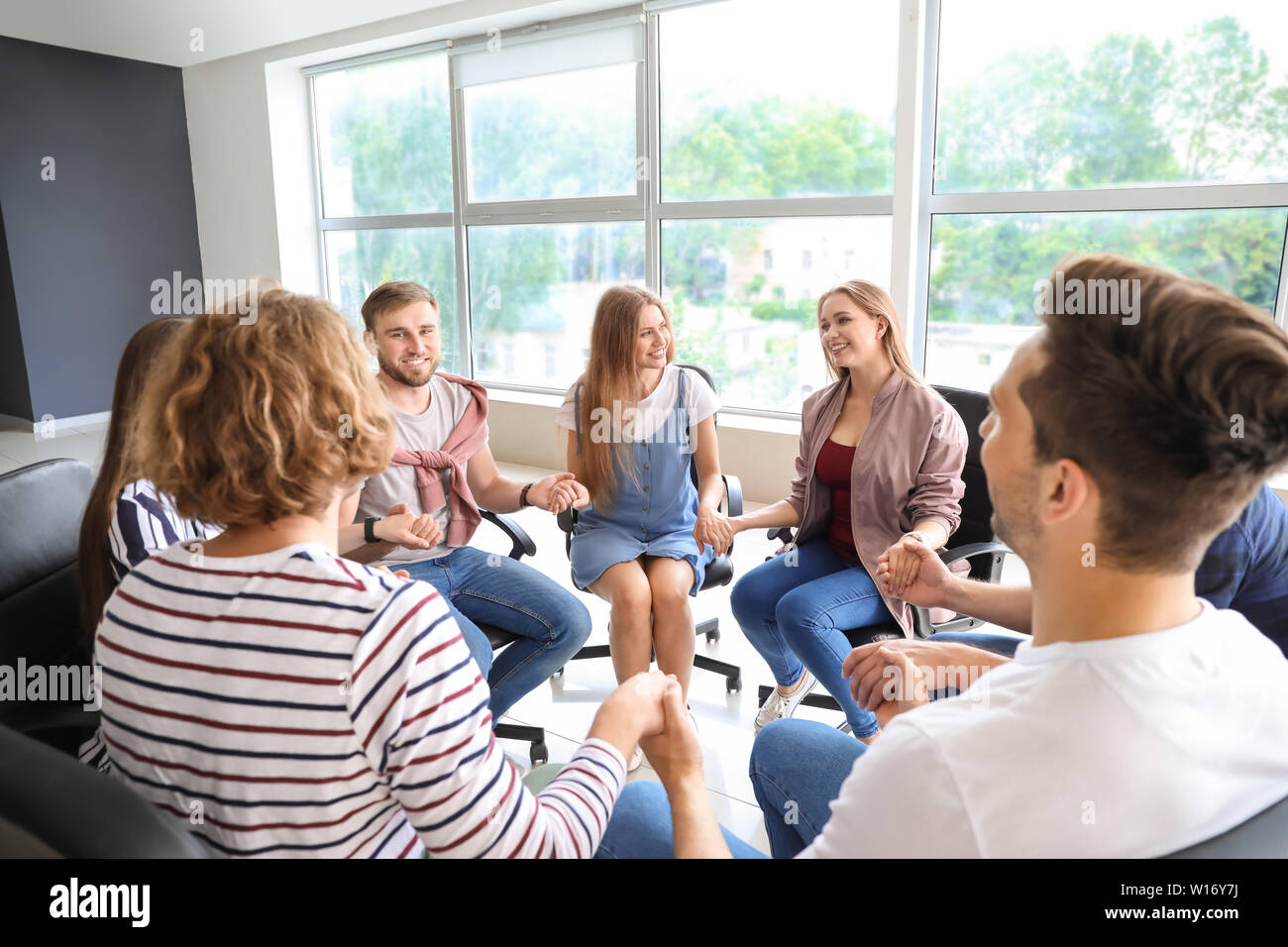 Young people holding hands together at group therapy session Stock ...