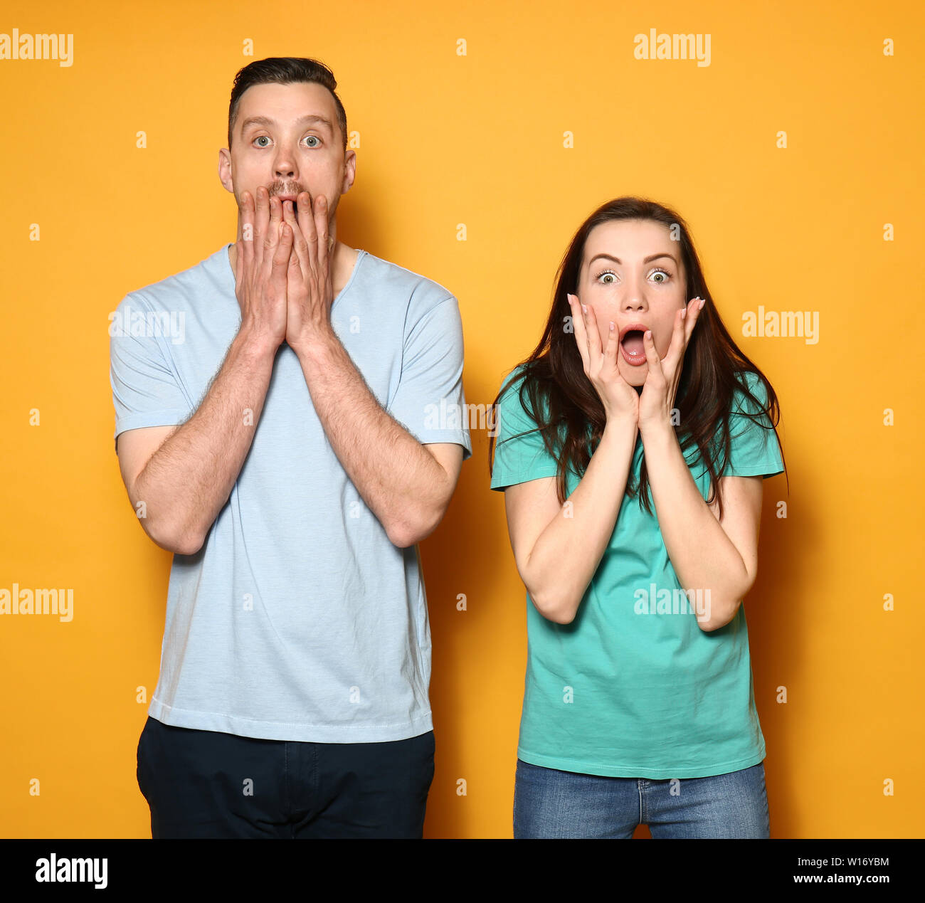 Afraid young couple on color background Stock Photo - Alamy