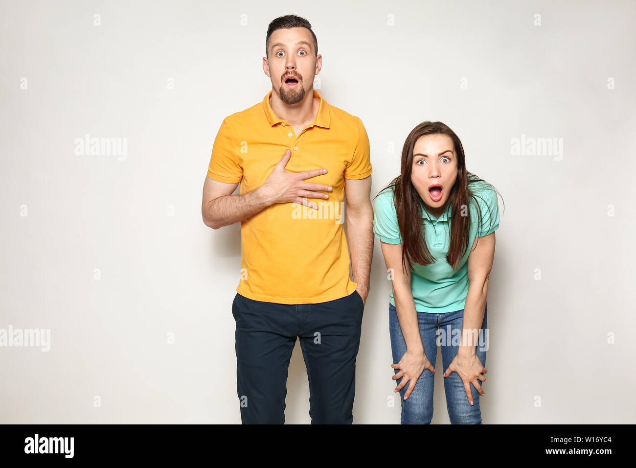 Shocked young couple on light background Stock Photo - Alamy