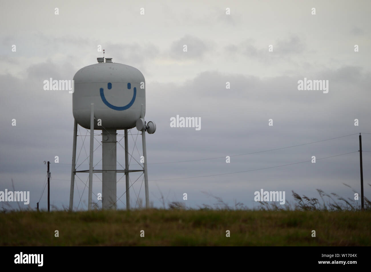 Happy, smiley face water tower in field on a cloudy day Stock Photo - Alamy