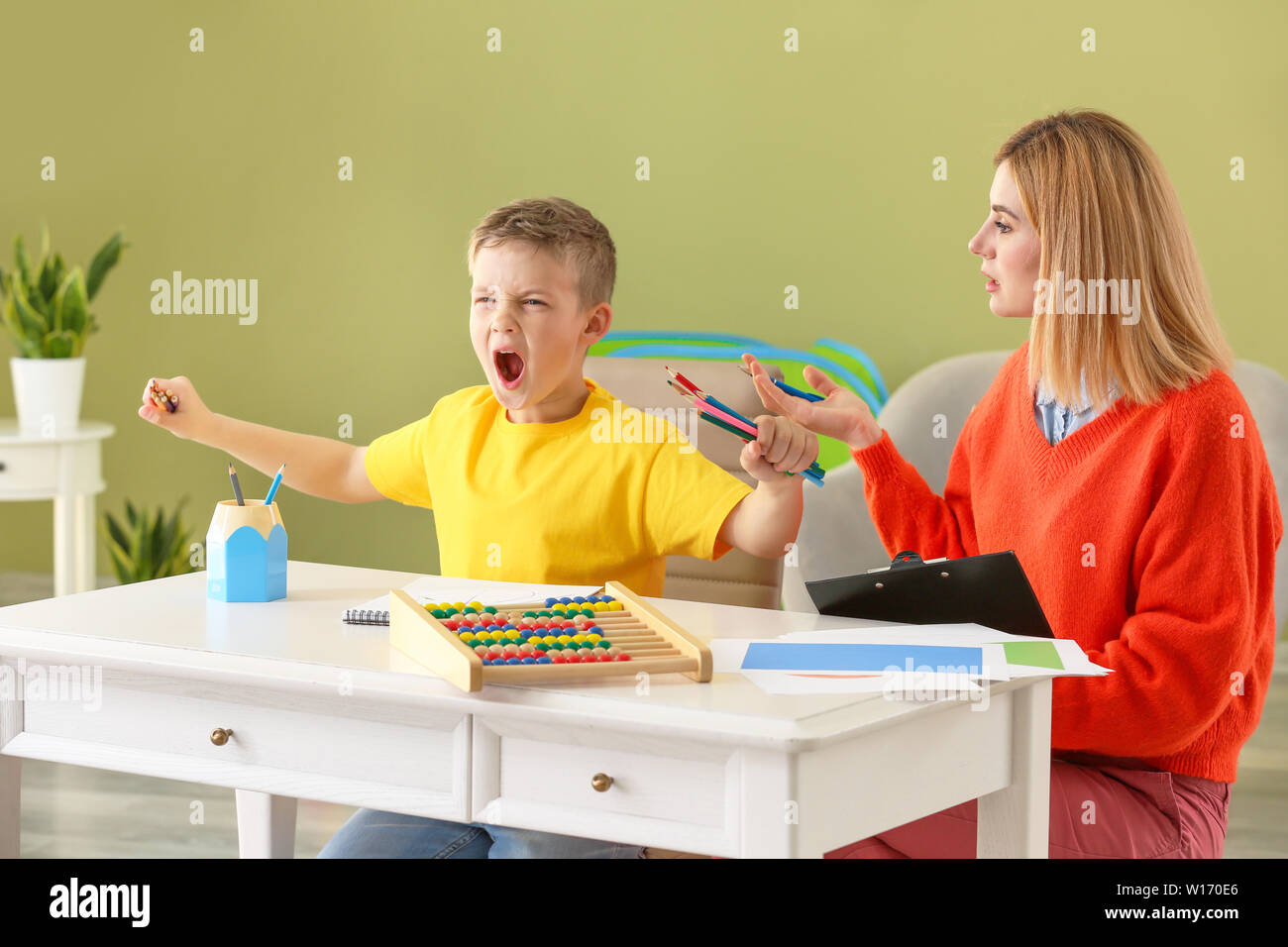 Female psychologist working with boy suffering from autistic disorder ...