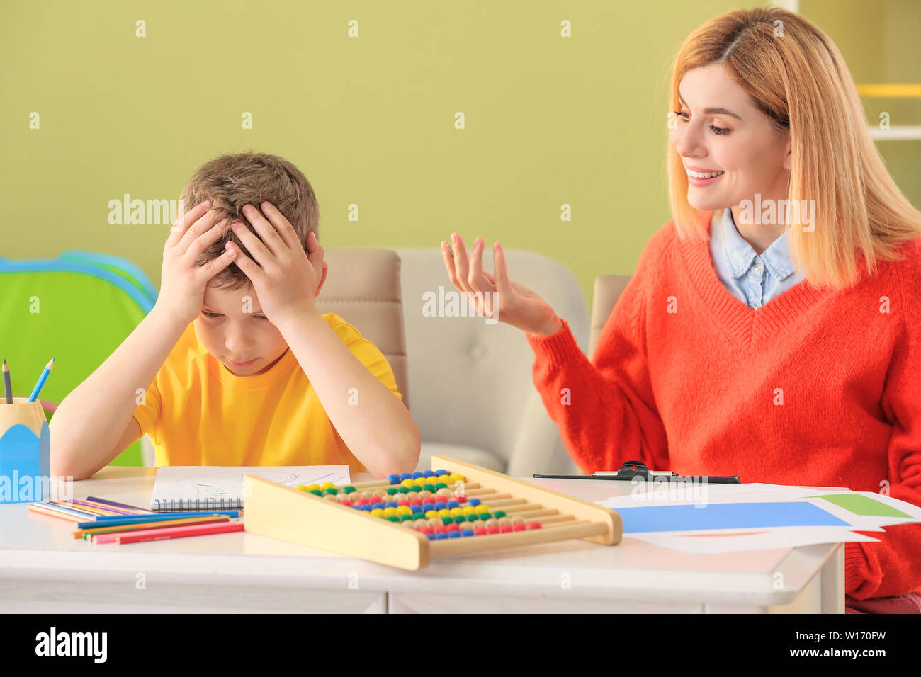 Female psychologist working with boy suffering from autistic disorder ...