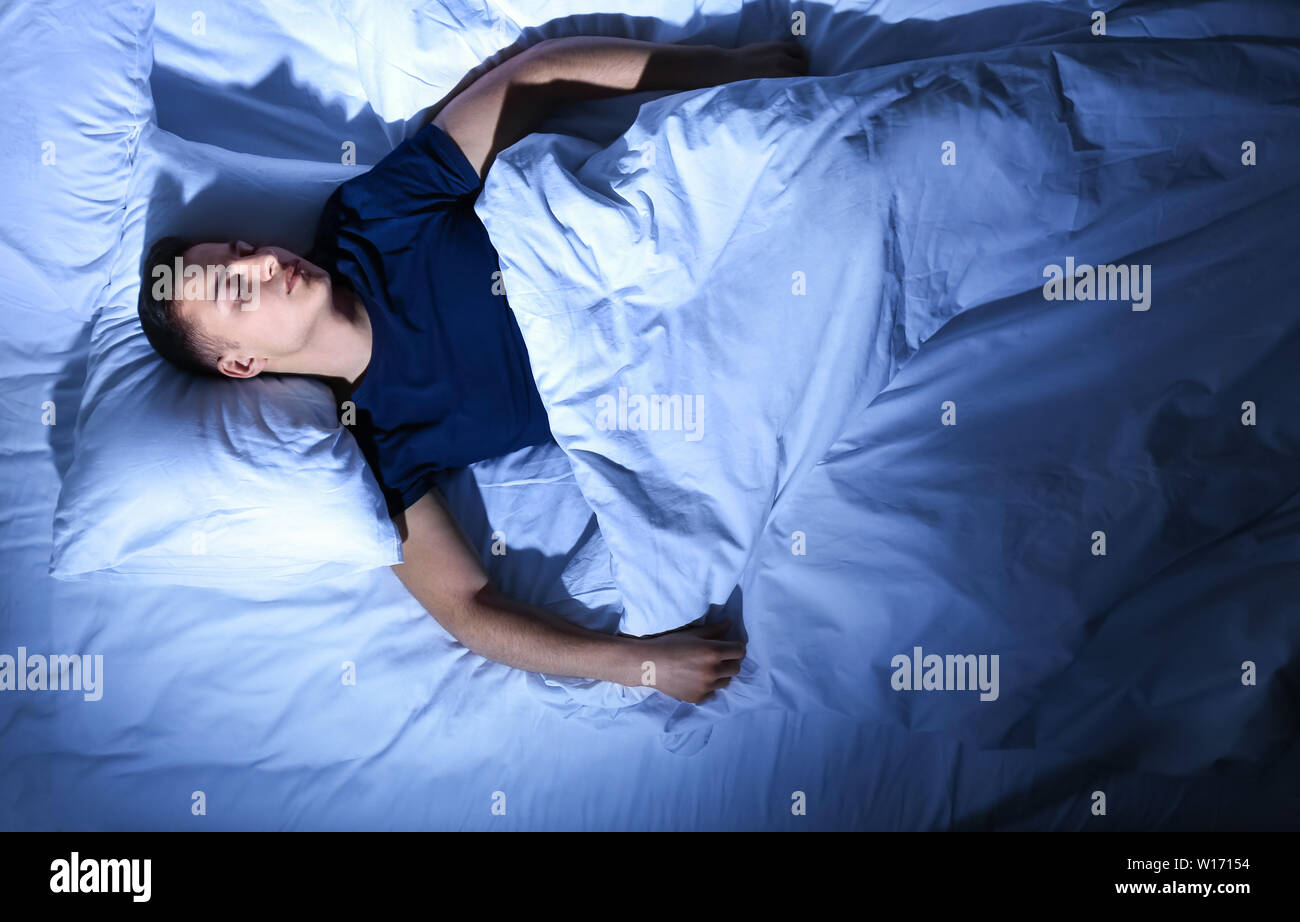 Young man sleeping in bed at night Stock Photo - Alamy