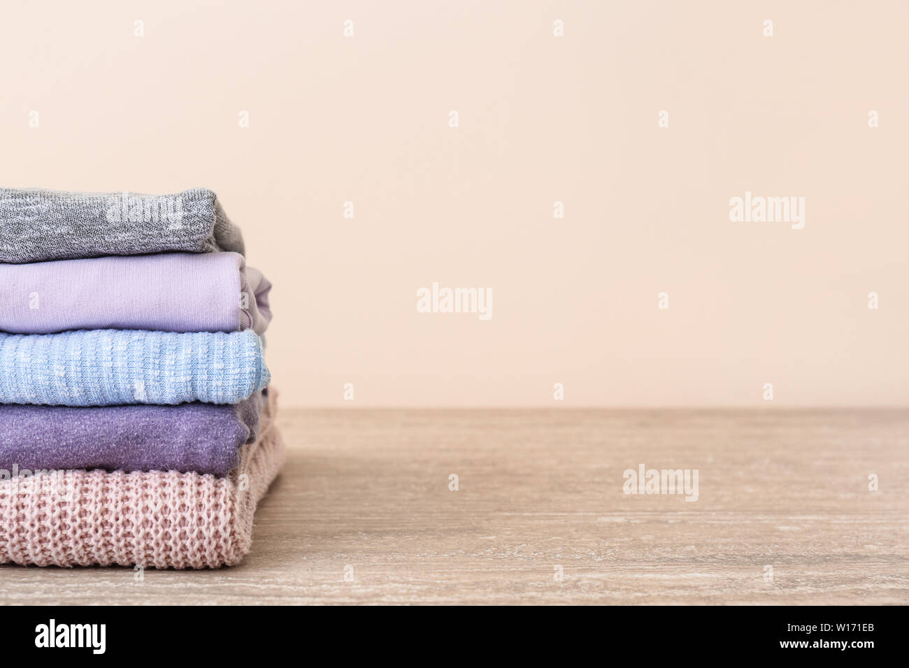 Stack of clean clothes on table against light background Stock Photo ...