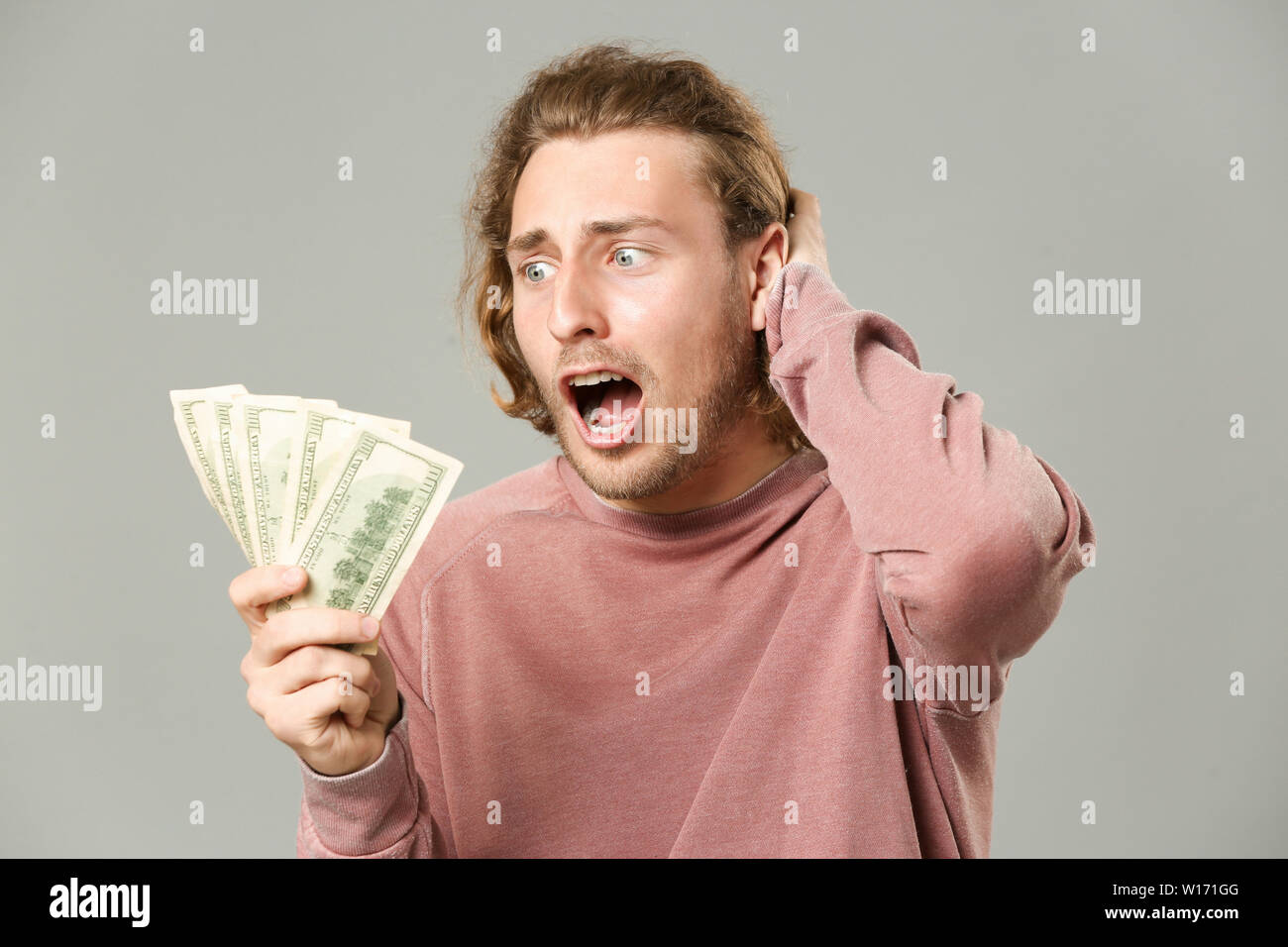 Happy man with money on grey background Stock Photo - Alamy