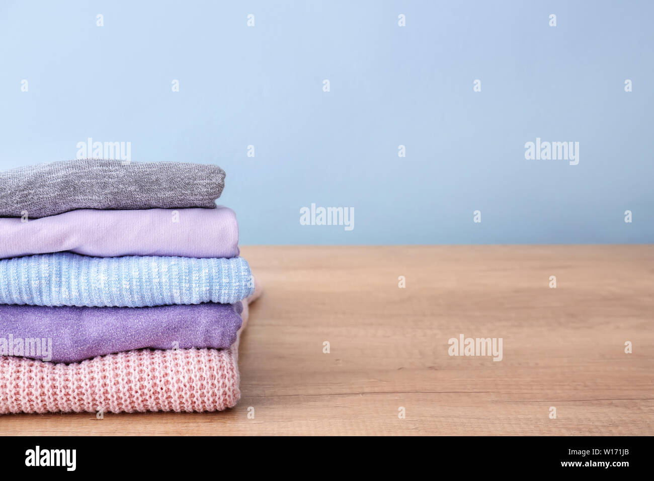 Stack of clean clothes on table against light background Stock Photo ...