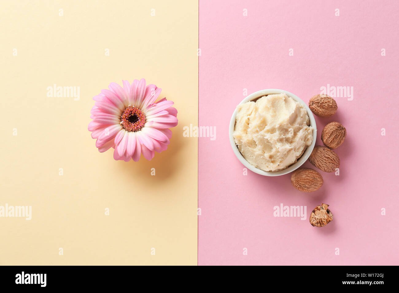 Shea butter with nuts and flower on color background Stock Photo - Alamy