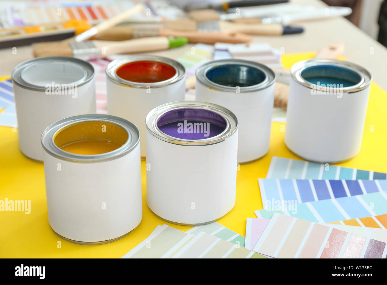 Cans of paints with palette samples on table Stock Photo - Alamy