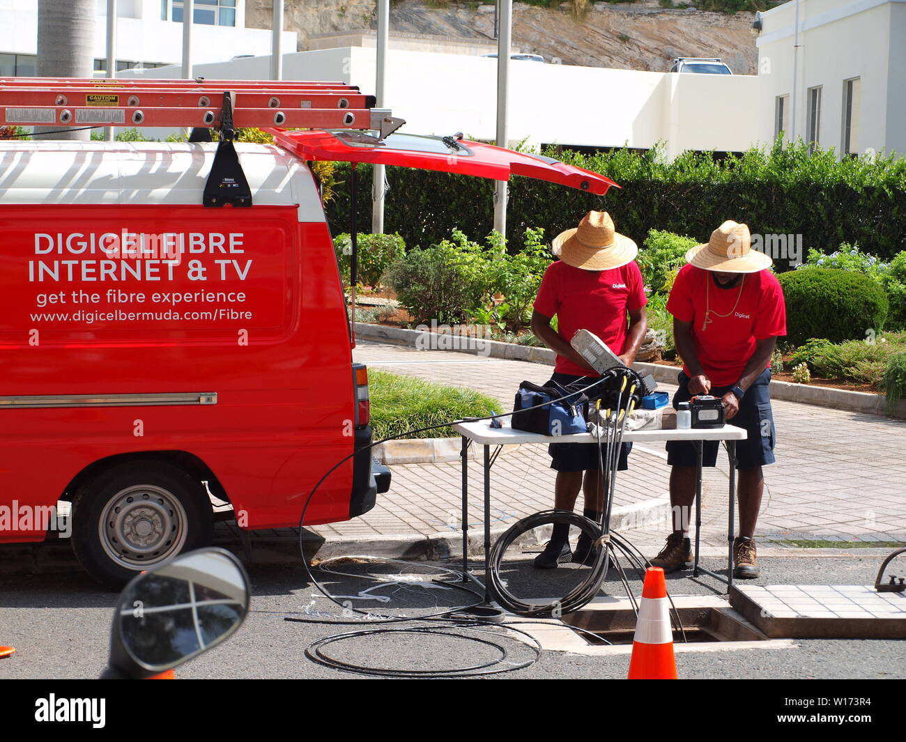 Local Bermuda utility workers in straw hats repairing fiber optic cable ...
