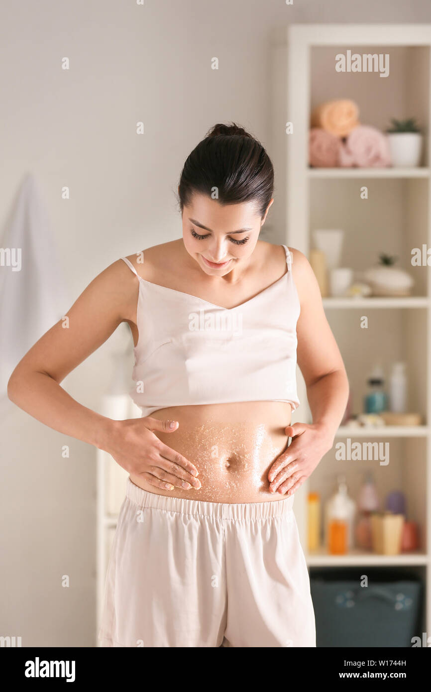 Beautiful young woman applying body scrub at home Stock Photo - Alamy