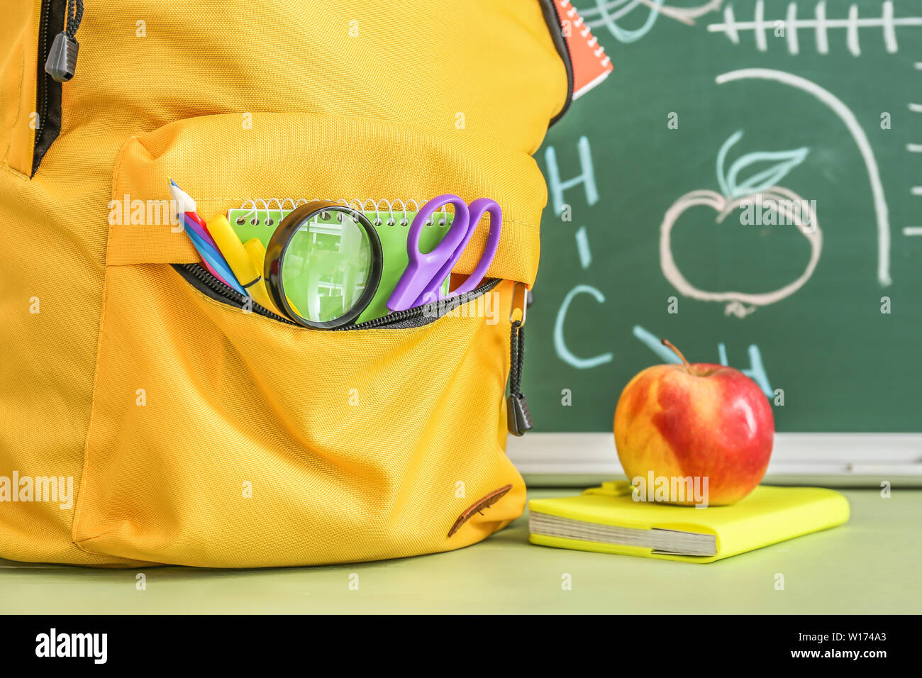 Backpack with school supplies on table in classroom Stock Photo - Alamy